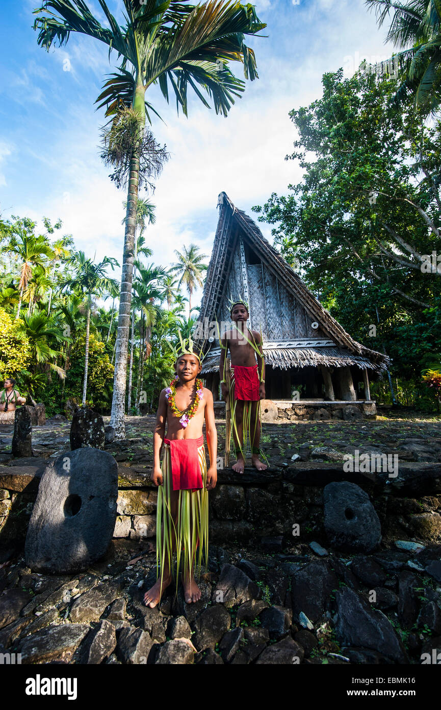 Two traditionally dressed boys standing in front of a traditional hut ...