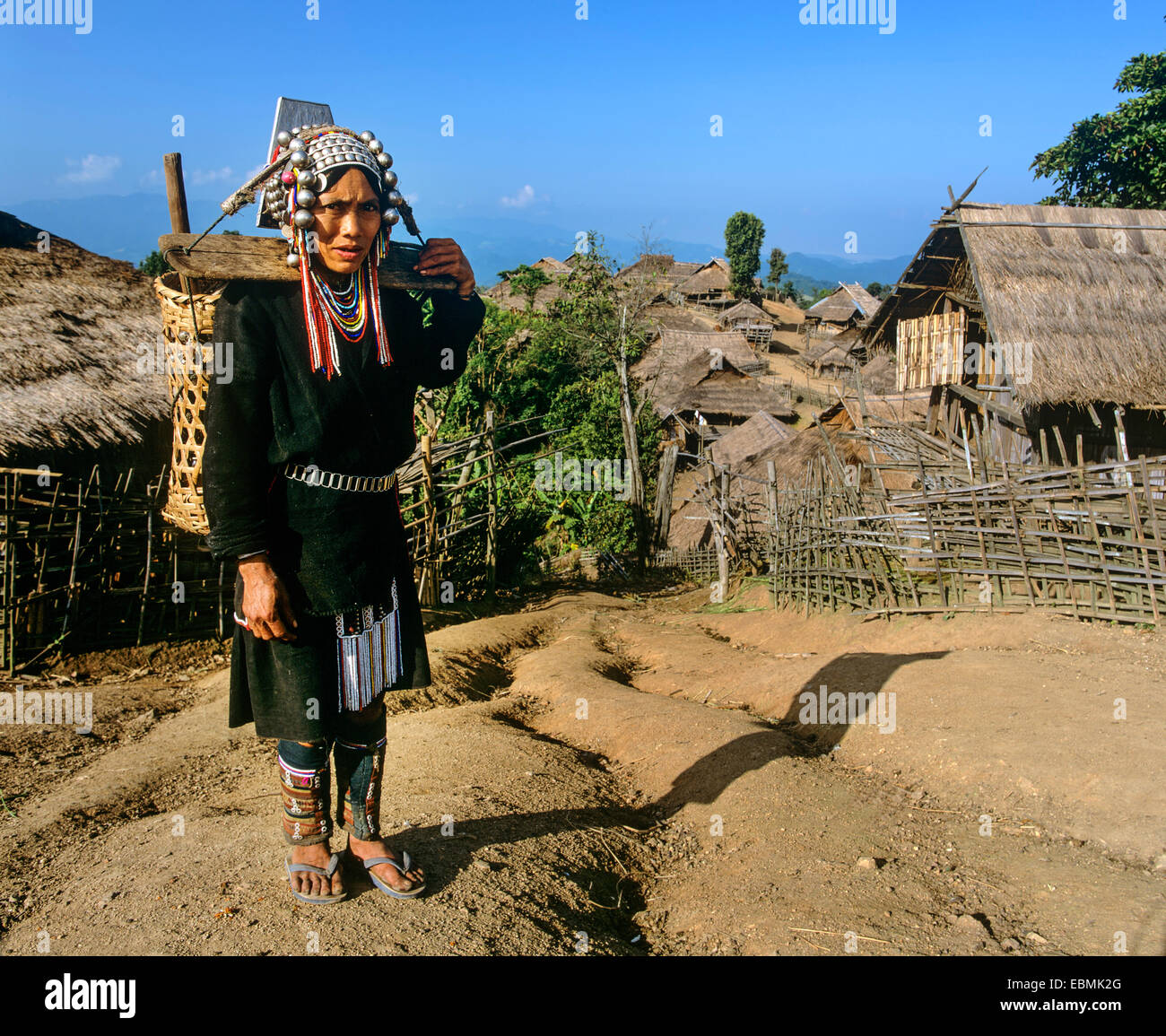 Akha woman in traditional costume with a pannier, in a mountain village ...