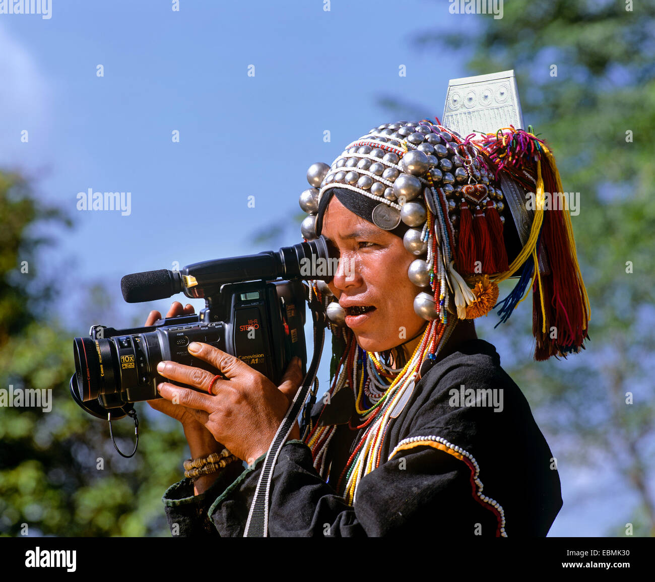 Akha woman in traditional costume and headdress with silver bells ...