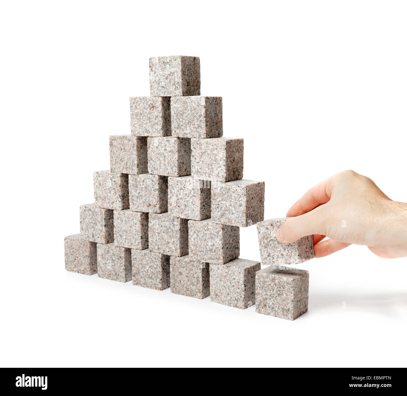 Hand removing one block of a pyramid made of small granite rock blocks ...