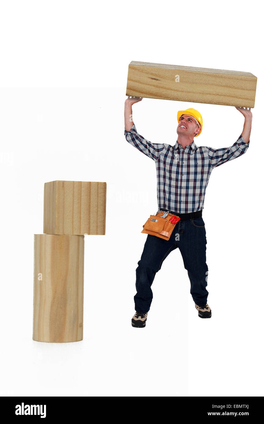 Man having difficulty lifting wooden block Stock Photo - Alamy