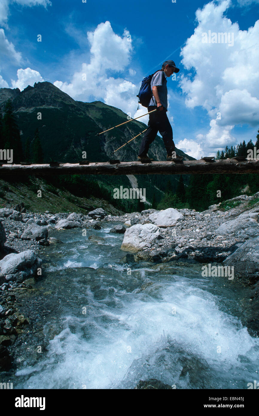 Hiker passing mountain creek over wooden bridge, Austria, Tyrol ...