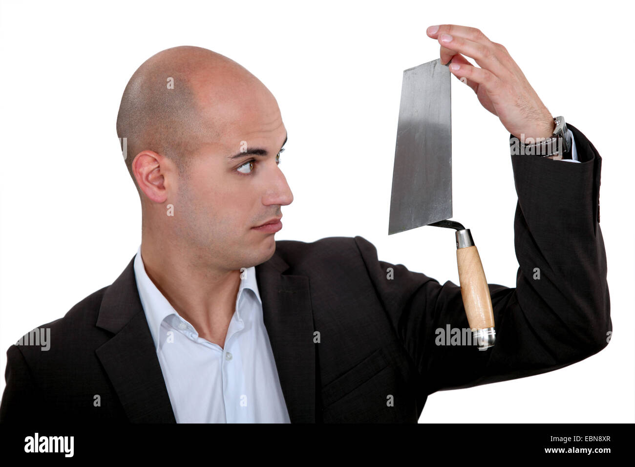 Businessman looking disbelievingly at a trowel Stock Photo - Alamy
