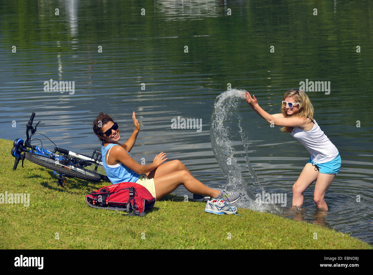 a young woman standing in shallow water and splashing water to her ...