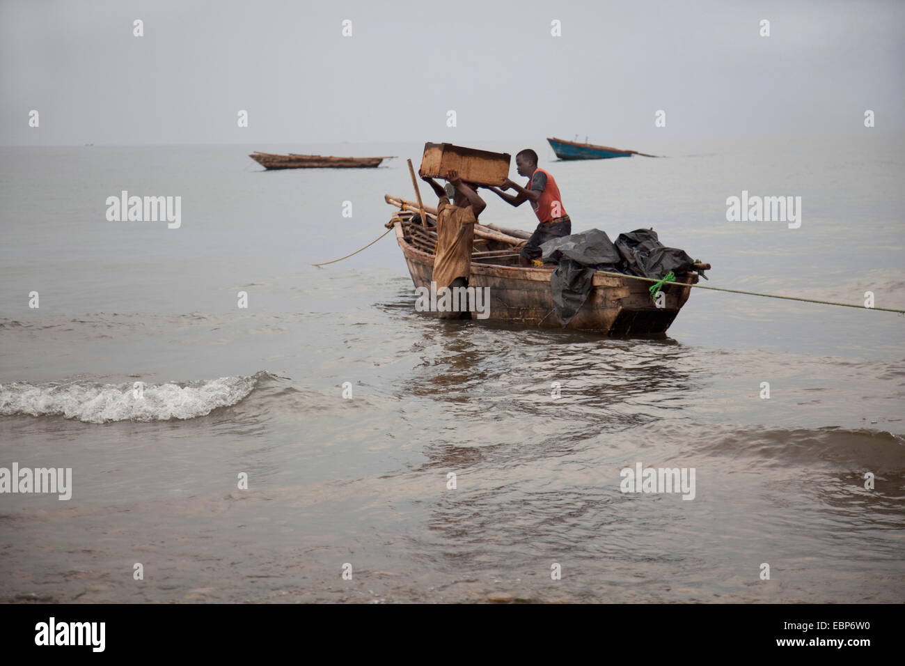 boy carrying wooden box with recently caught fish on his head from a ...