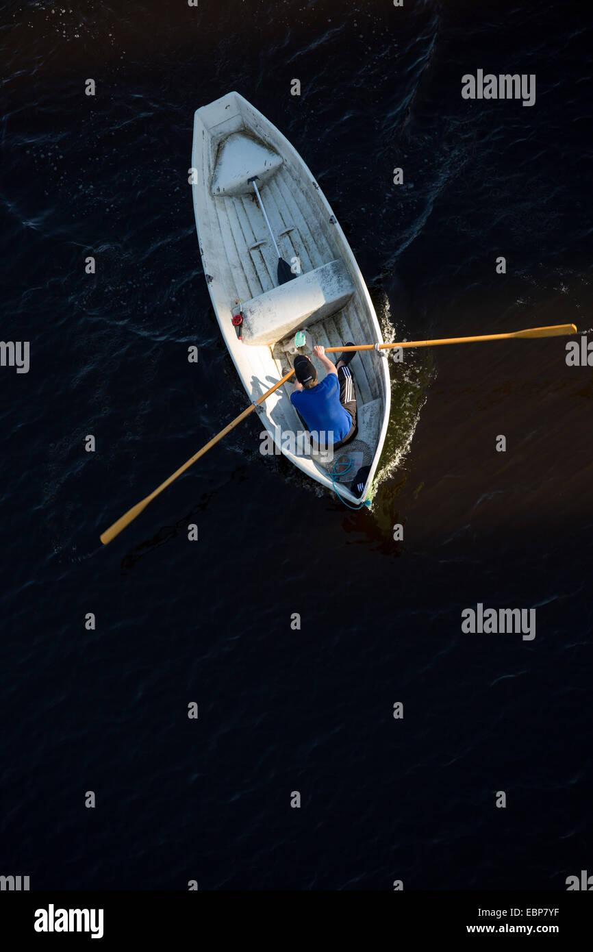 Aerial view of a man rowing a fiberglass rowboat / skiff / dinghy ...