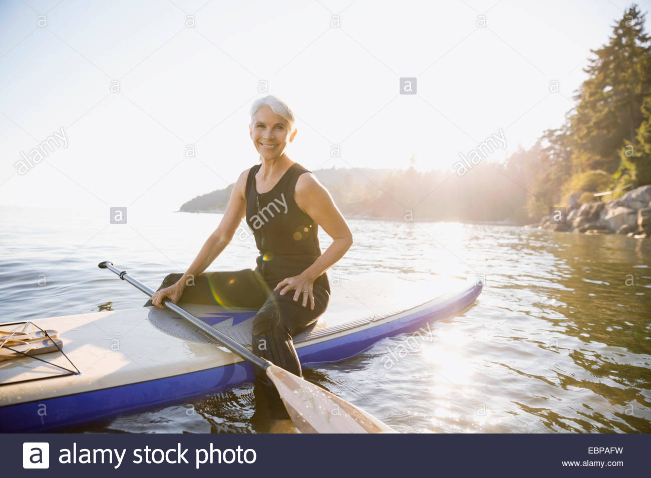 Woman sitting on paddle board hi-res stock photography and images - Alamy