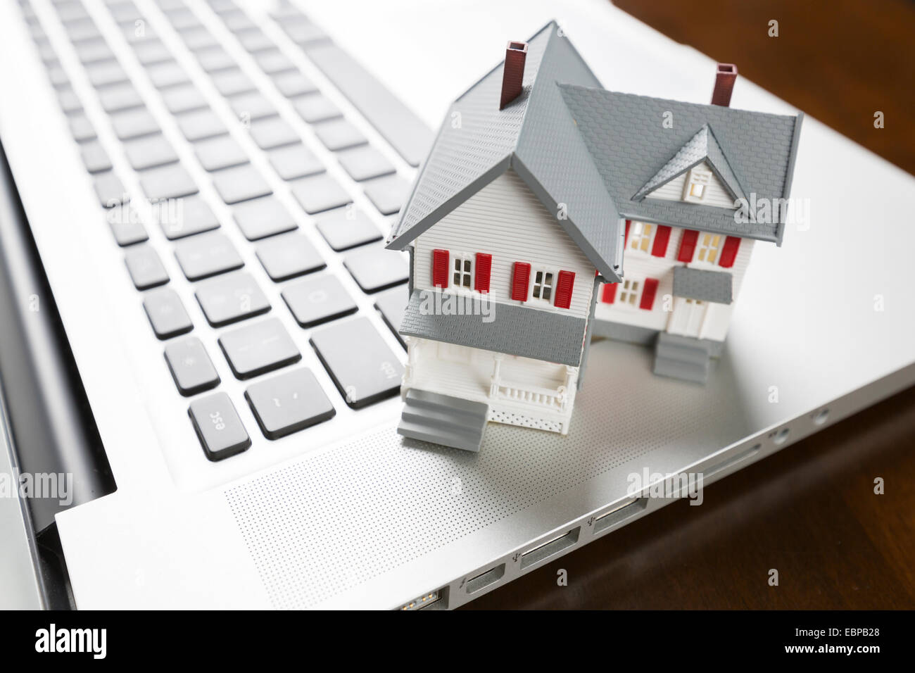 Miniature House And Laptop Computer Resting on Desktop Stock Photo - Alamy