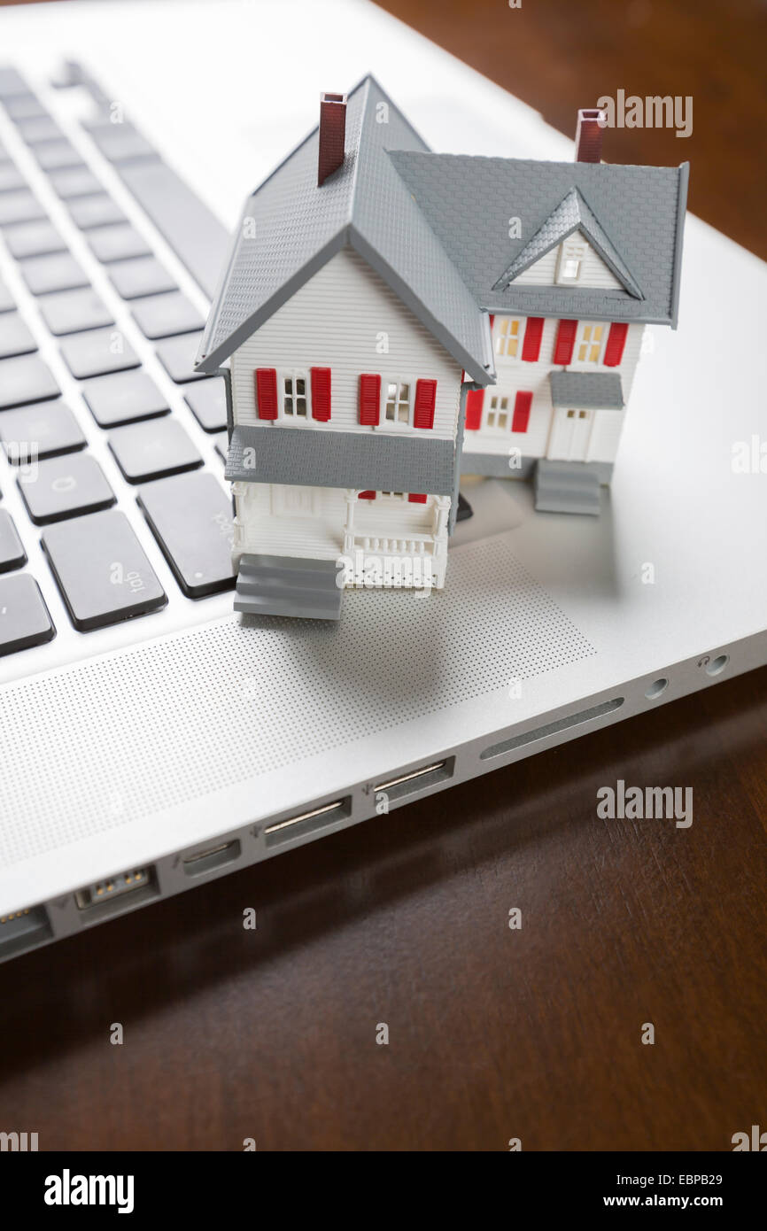 Miniature House And Laptop Computer Resting on Desktop Stock Photo - Alamy
