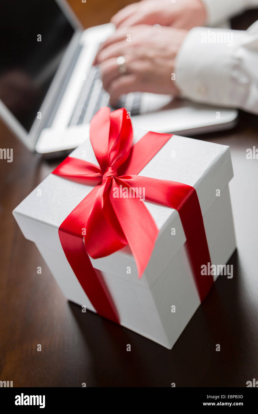 White Gift Box with Red Ribbon and Bow Near Man Typing on Laptop ...
