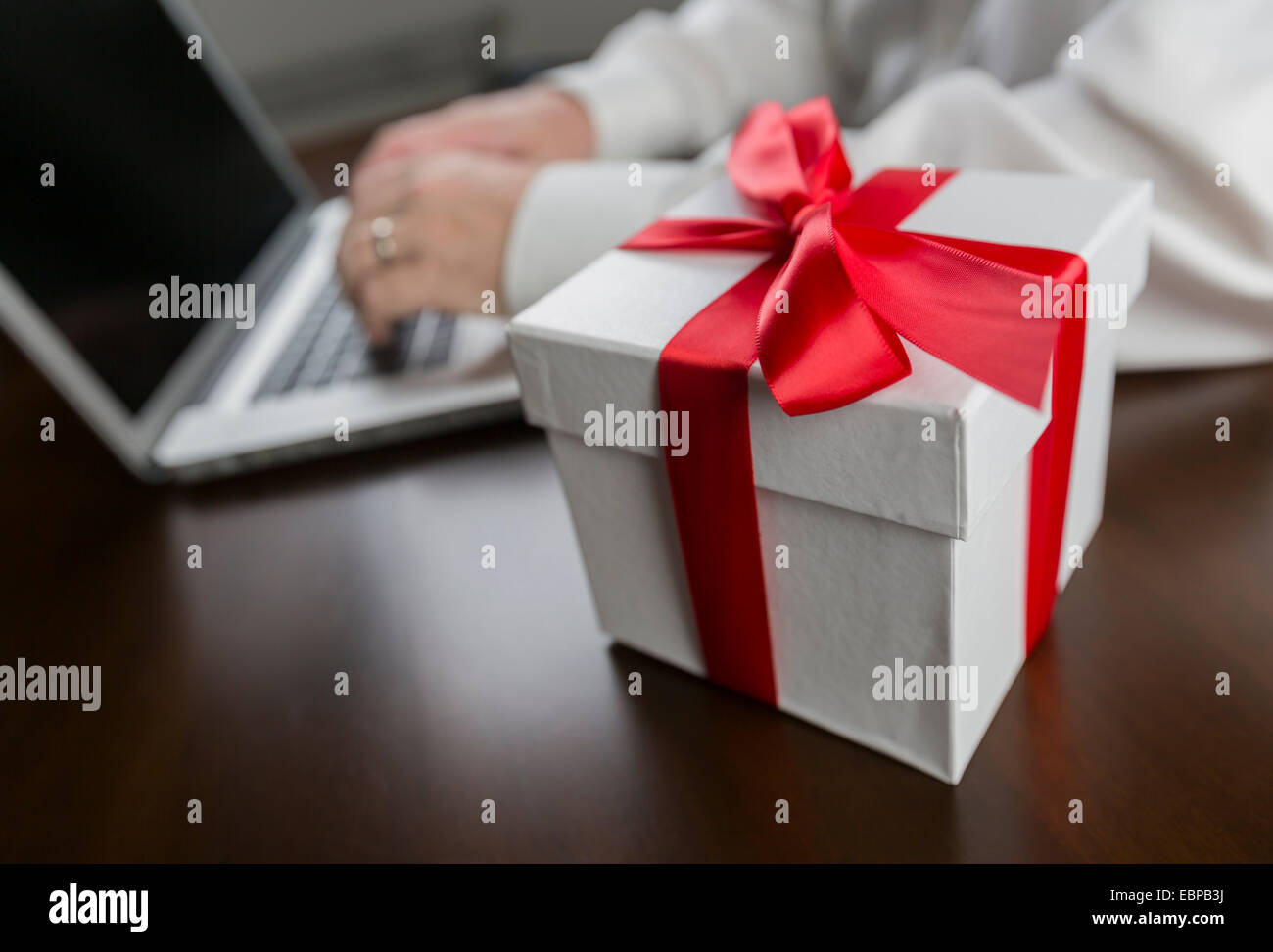White Gift Box with Red Ribbon and Bow Near Man Typing on Laptop ...