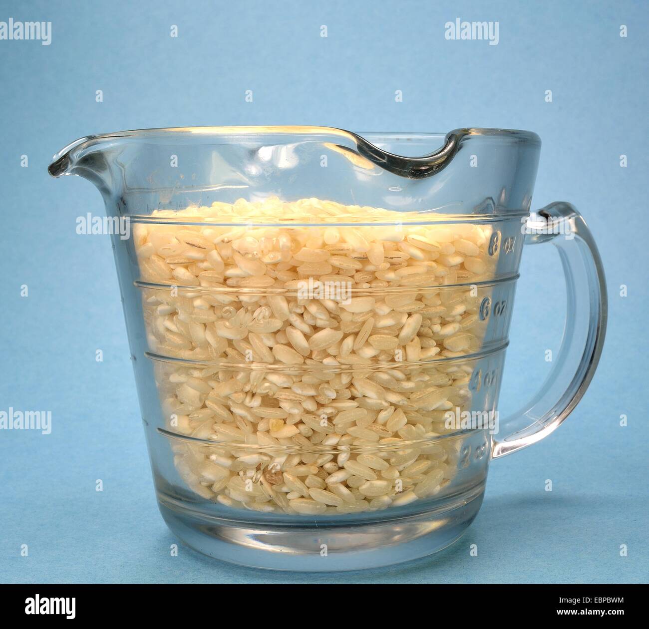 Measuring cup filled with brown rice on a blue background Stock Photo ...