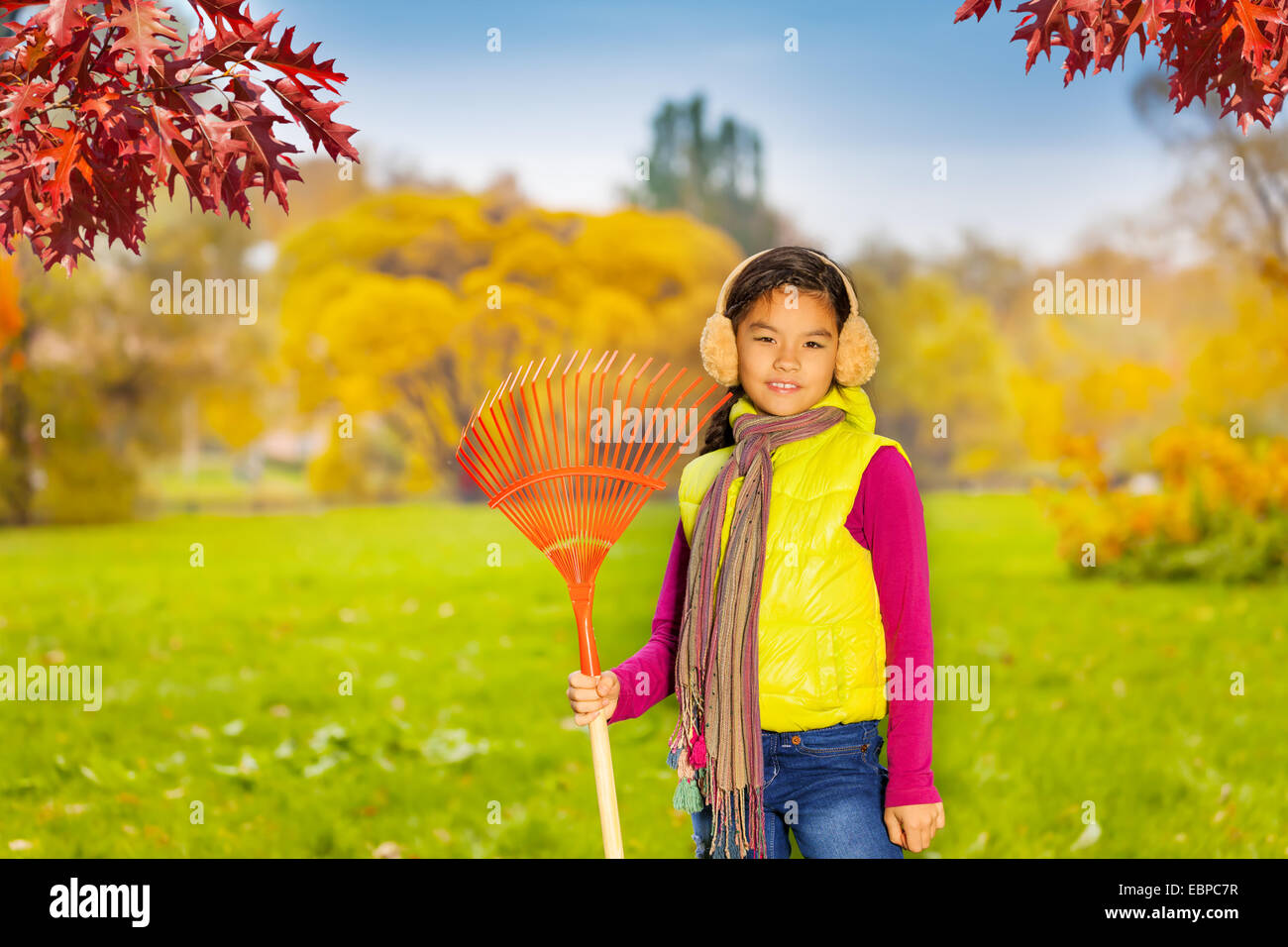 Cheerful Asian girl with big red rake stands alone Stock Photo - Alamy