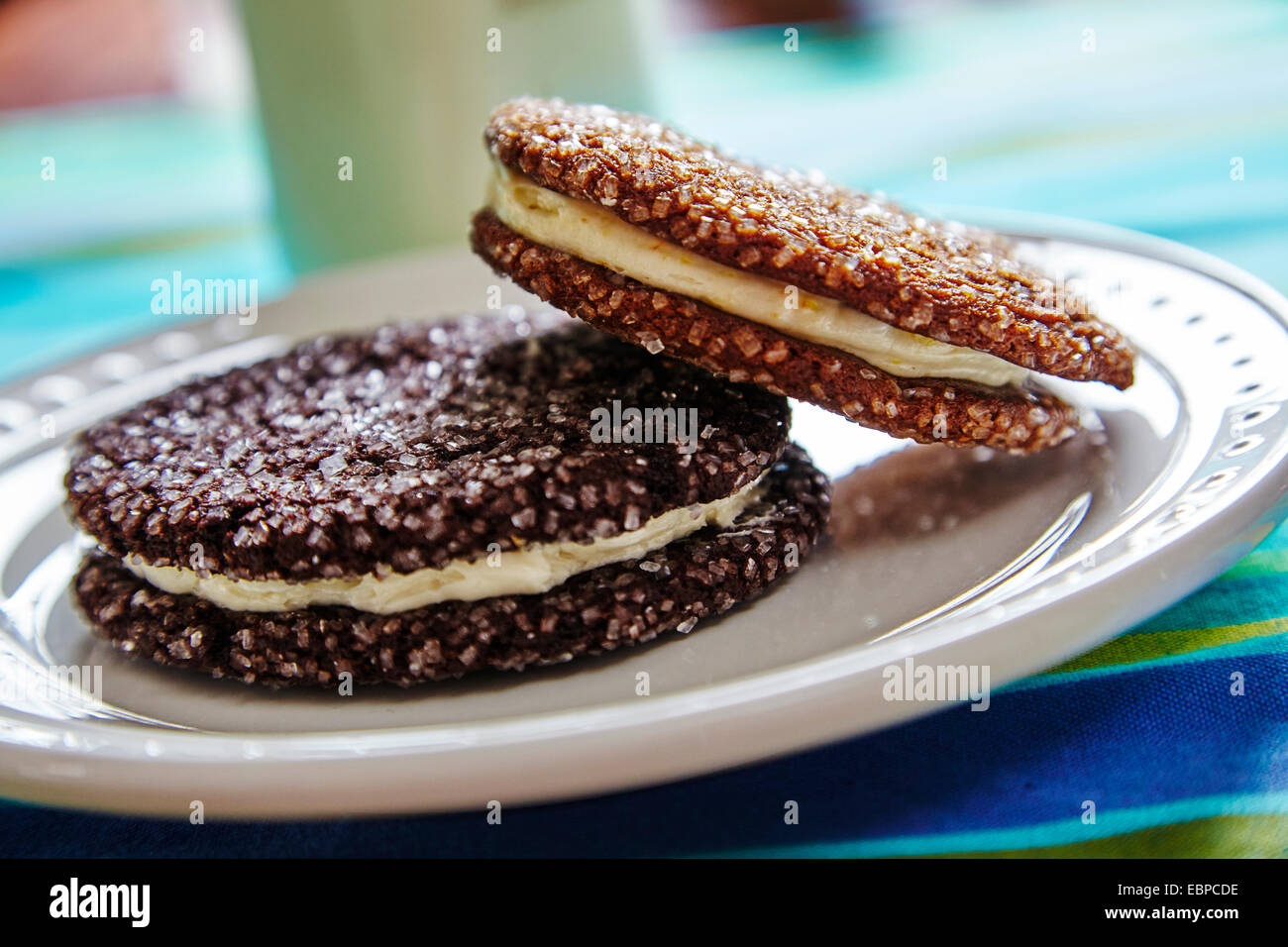 Two chocolate cookies filled with vanilla filling sugar on top on a ...