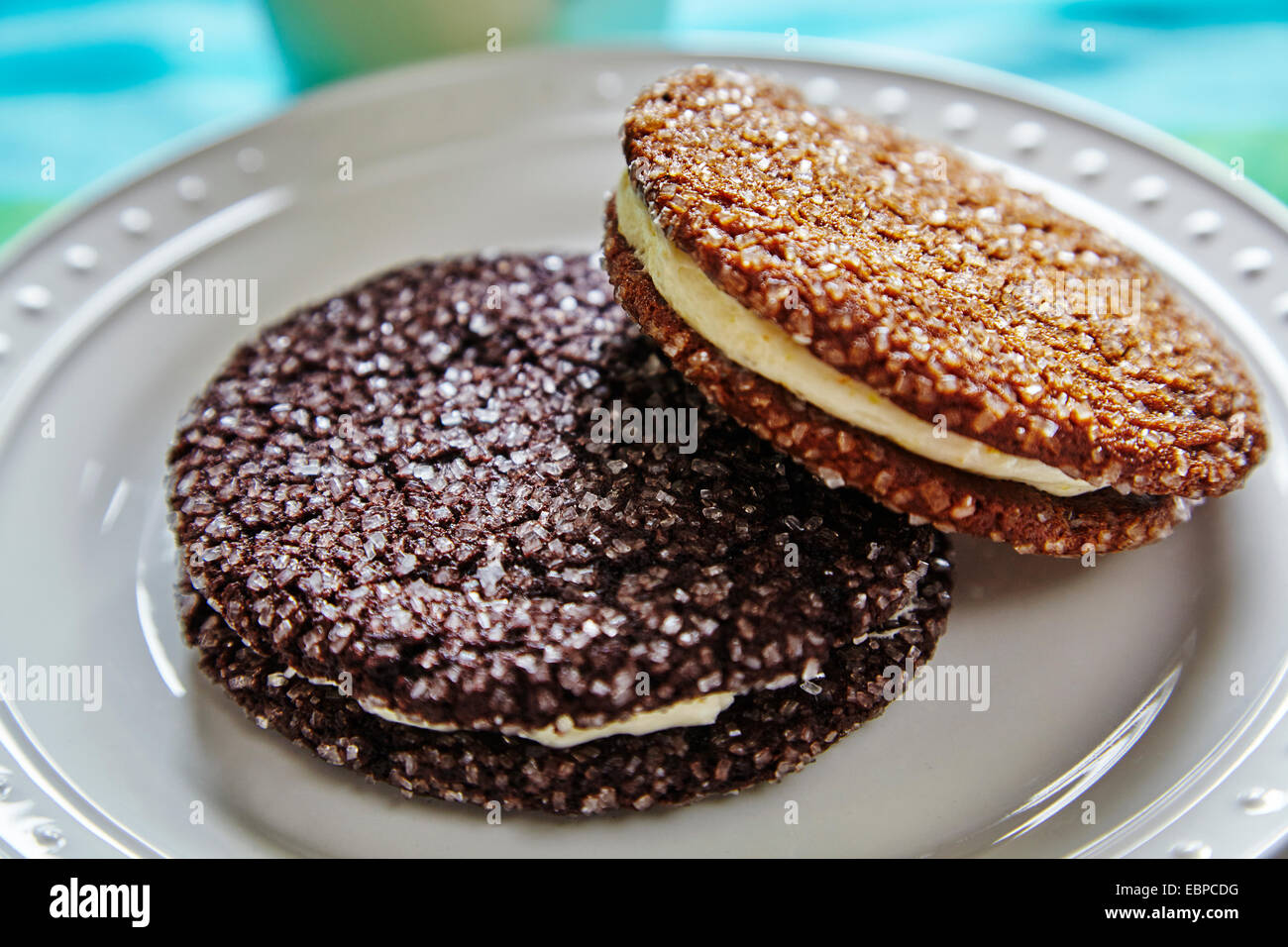 Two chocolate cookies filled with vanilla filling sugar on top on a ...