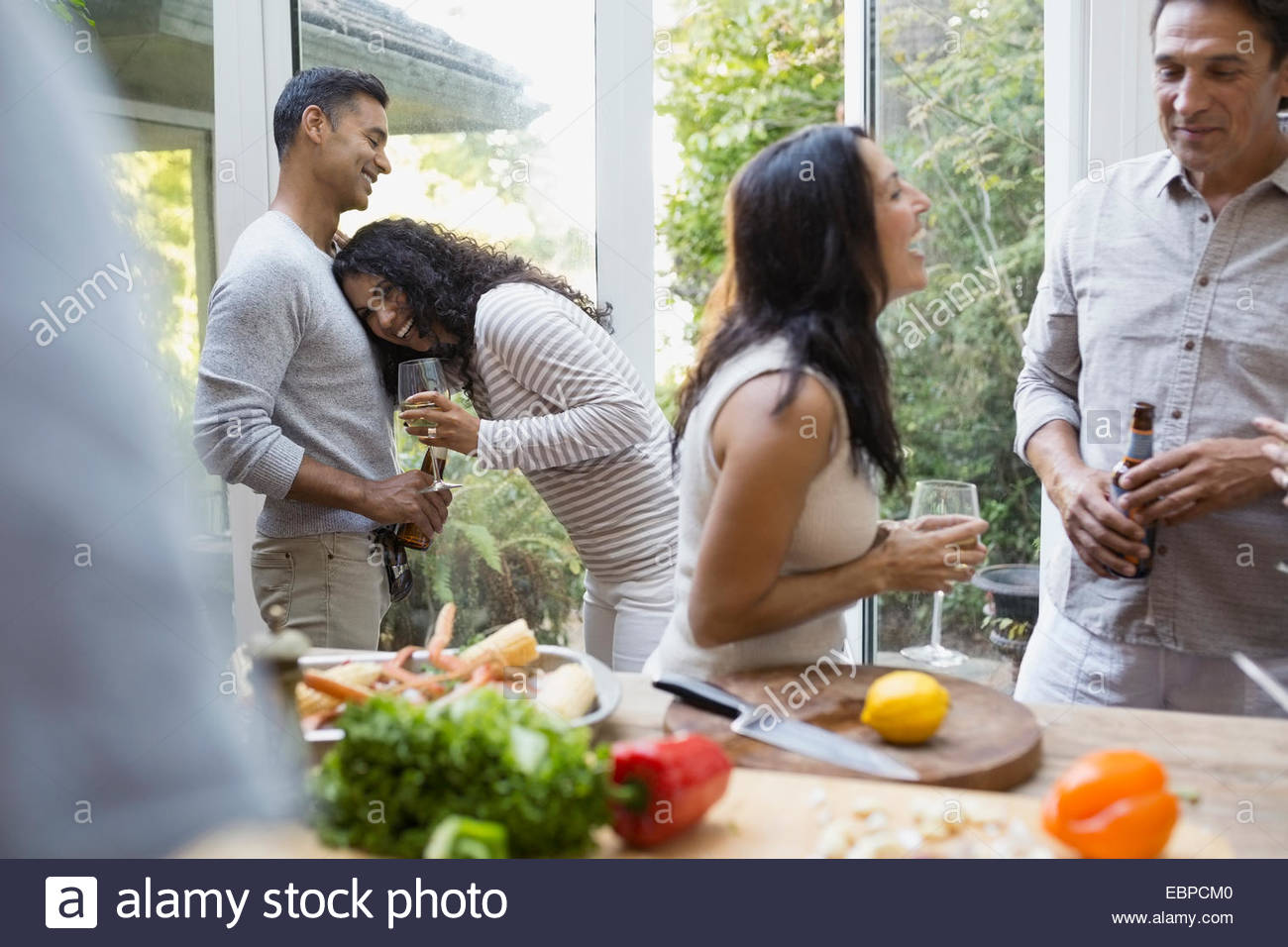 Friends drinking and laughing in kitchen Stock Photo - Alamy