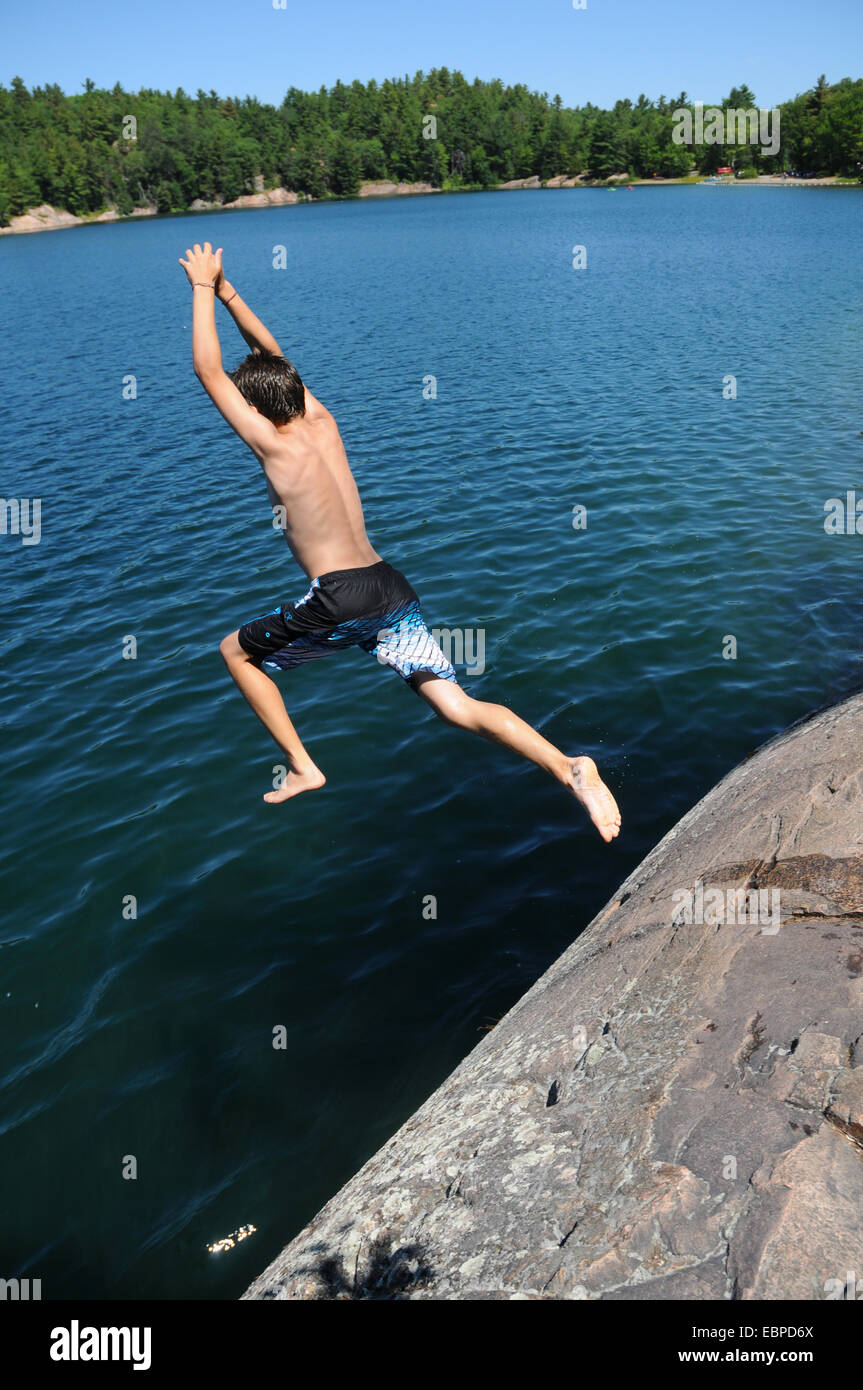 Kid jump to a lake from a rock Stock Photo - Alamy