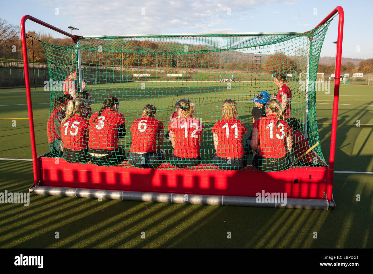 A ladies hockey team having a half-time talk from their coach while ...