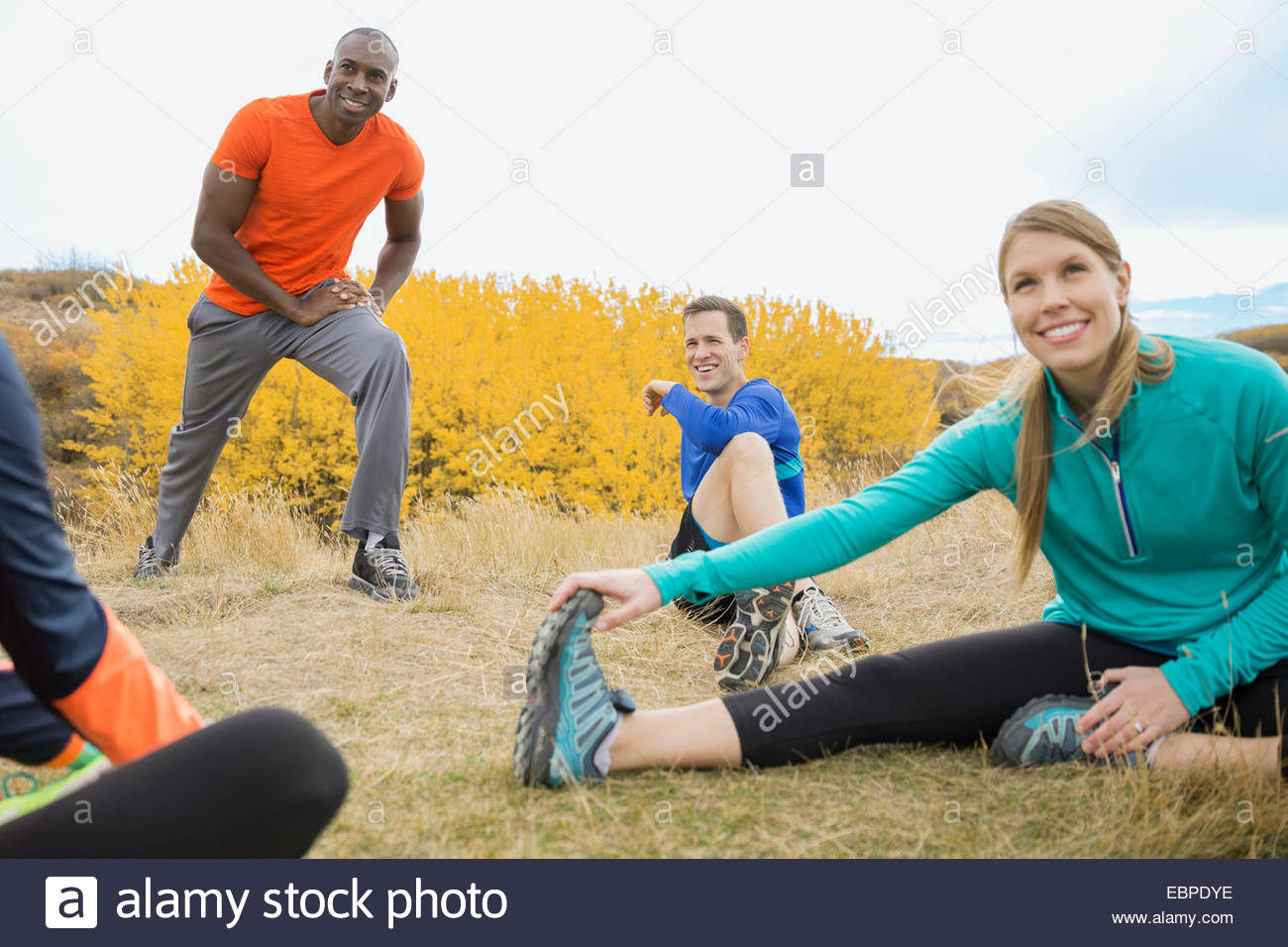 Runners stretching in field Stock Photo - Alamy