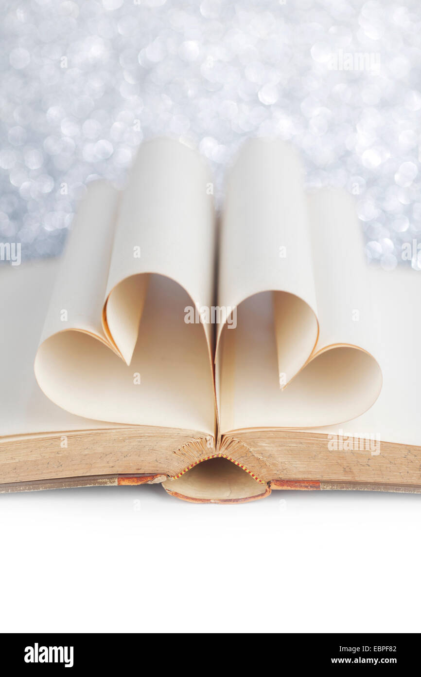 Pages of open book rolled in heart shape on glitter background Stock ...