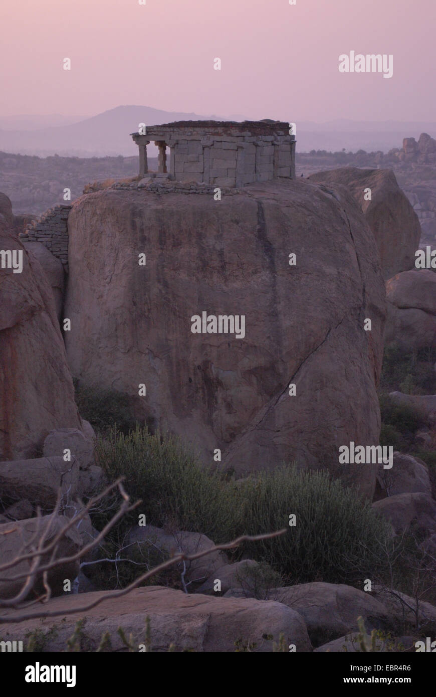 A huge boulder with a temple on top at sunset Stock Photo - Alamy