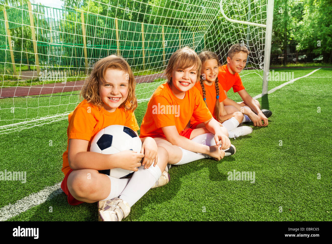 Kids sitting together on field near woodwork Stock Photo - Alamy