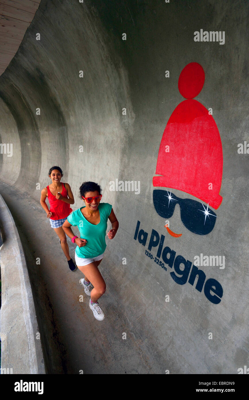 two young women running on the bobsleigh track in summer, France ...