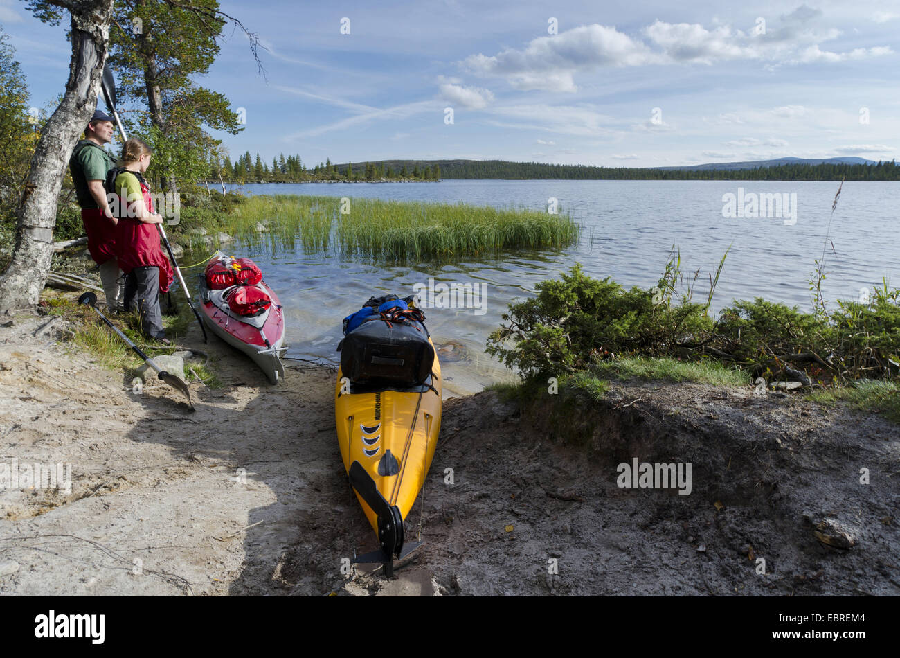 couple standing next to kayaks at the lakeshore and looking to Rogen ...