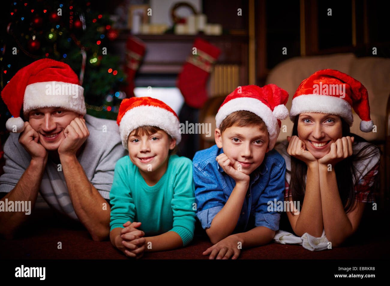 Parents and kids in Santa caps looking at camera Stock Photo - Alamy