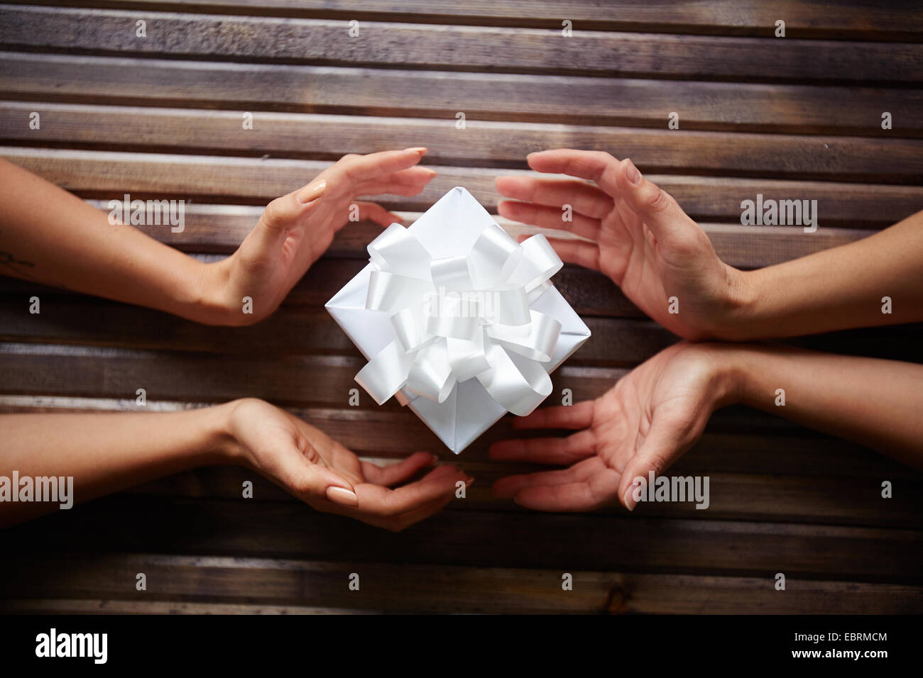 Hands surrounding a little gift box Stock Photo - Alamy