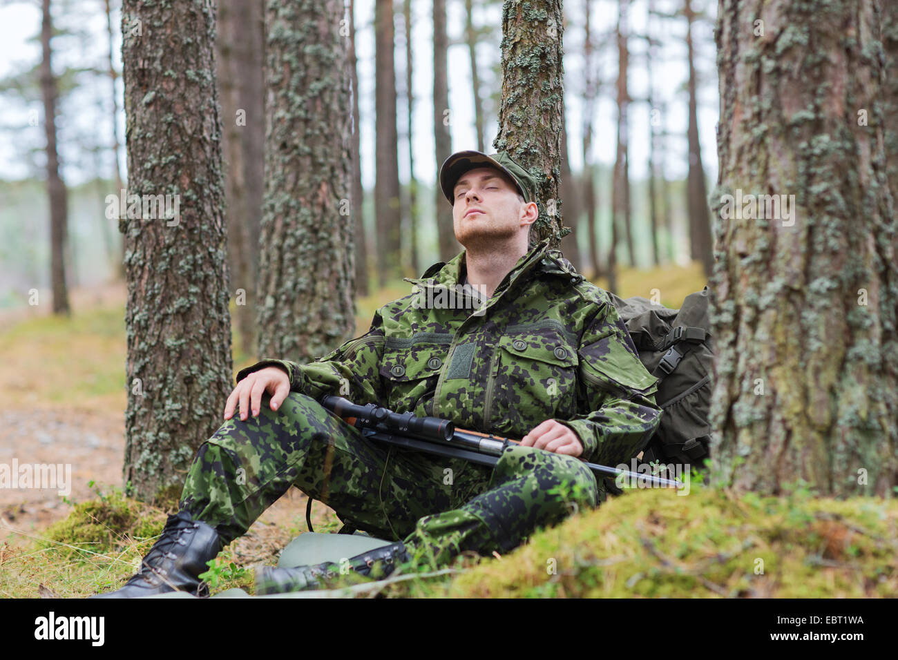 soldier or hunter with gun sleeping in forest Stock Photo - Alamy