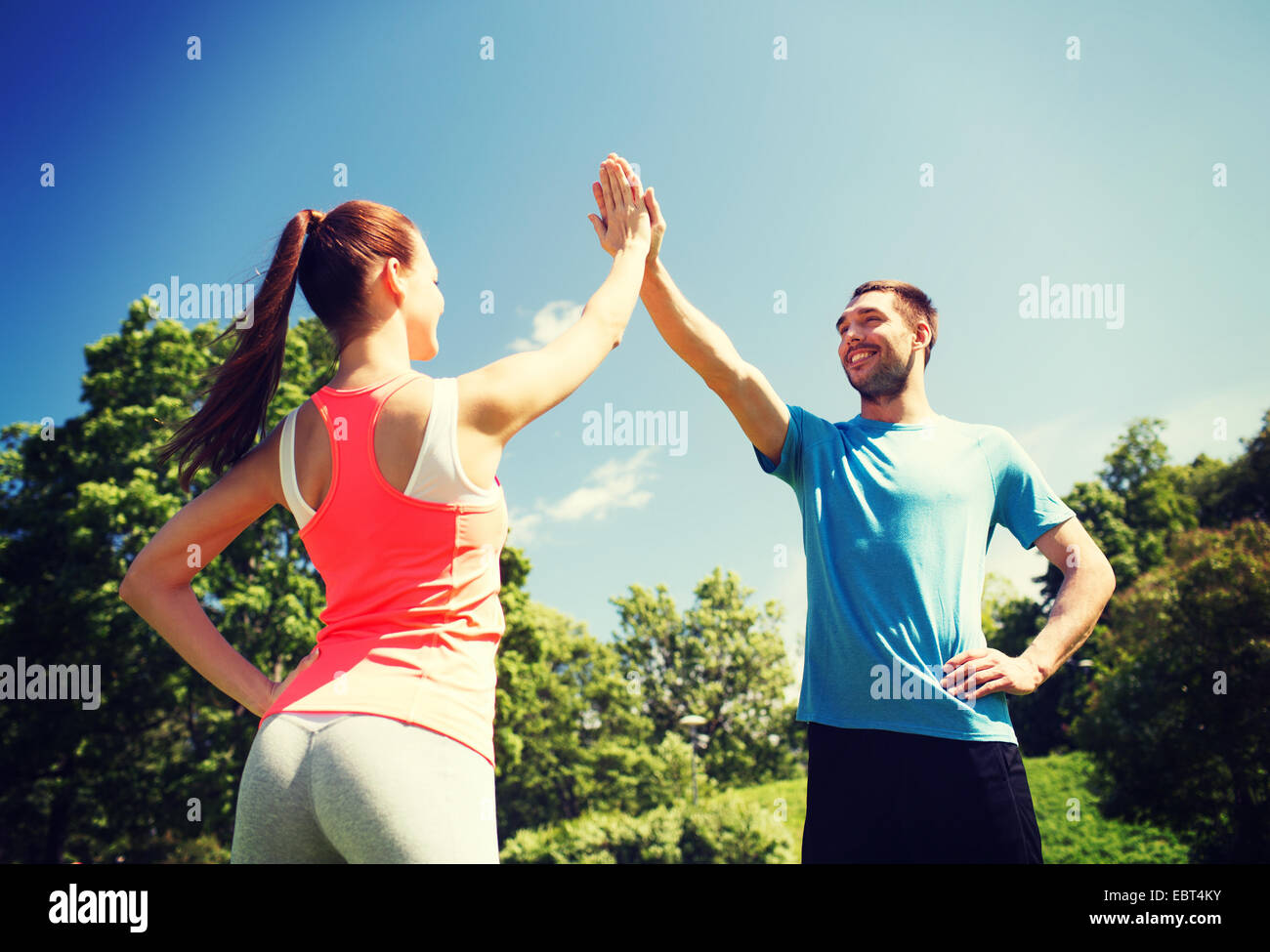 two smiling people making high five outdoors Stock Photo - Alamy