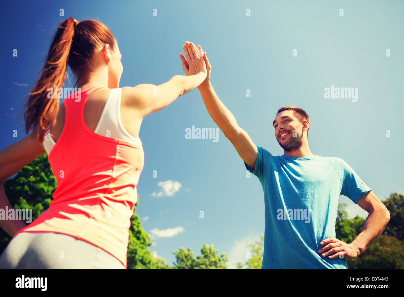 two smiling people making high five outdoors Stock Photo - Alamy