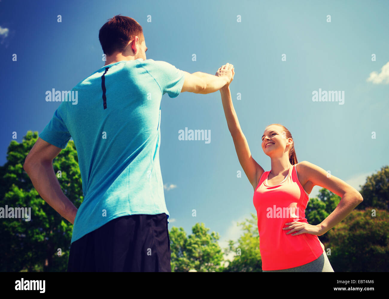 two smiling people making high five outdoors Stock Photo - Alamy