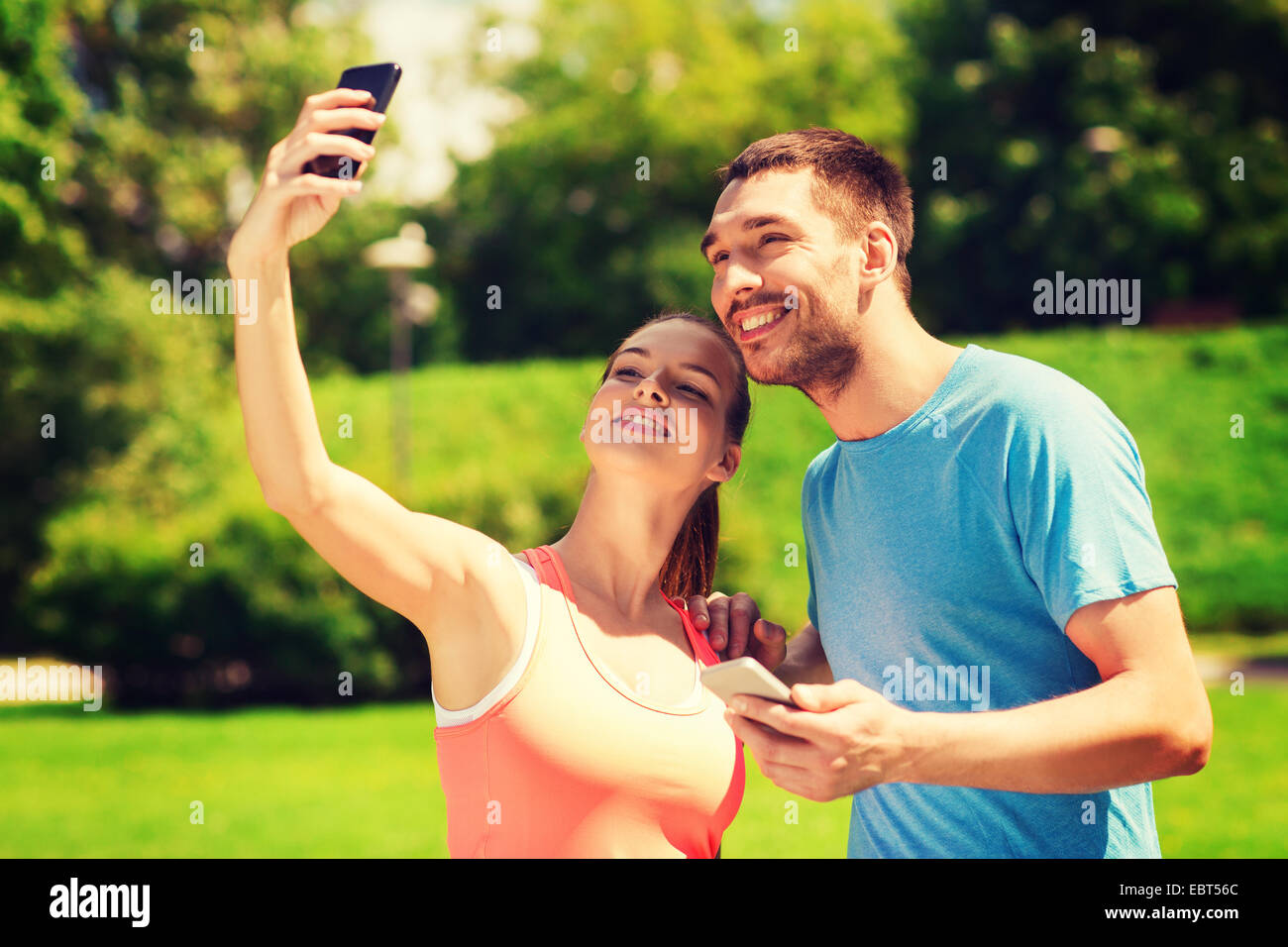 two smiling people with smartphones outdoors Stock Photo - Alamy