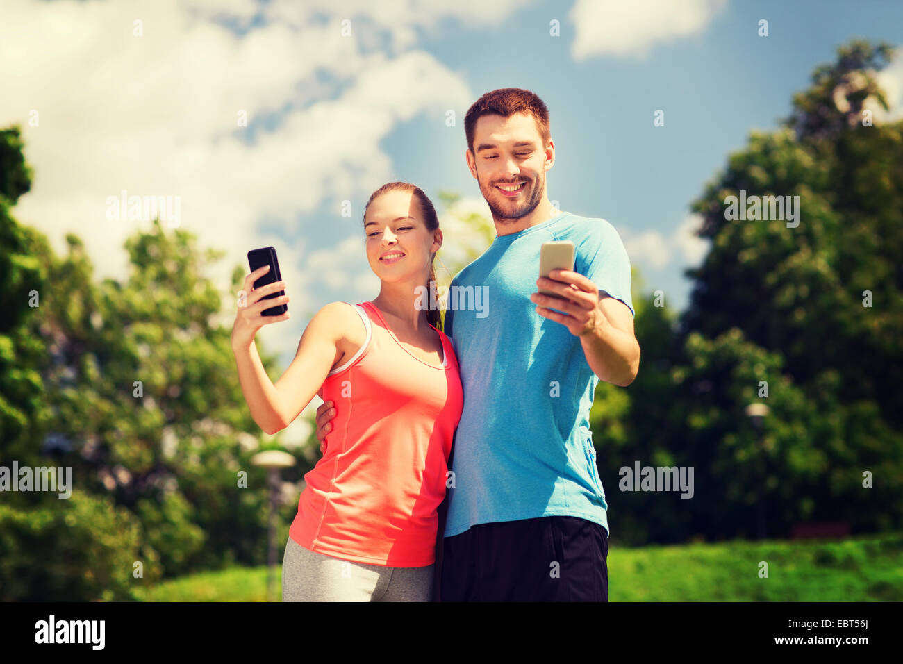 two smiling people with smartphones outdoors Stock Photo - Alamy