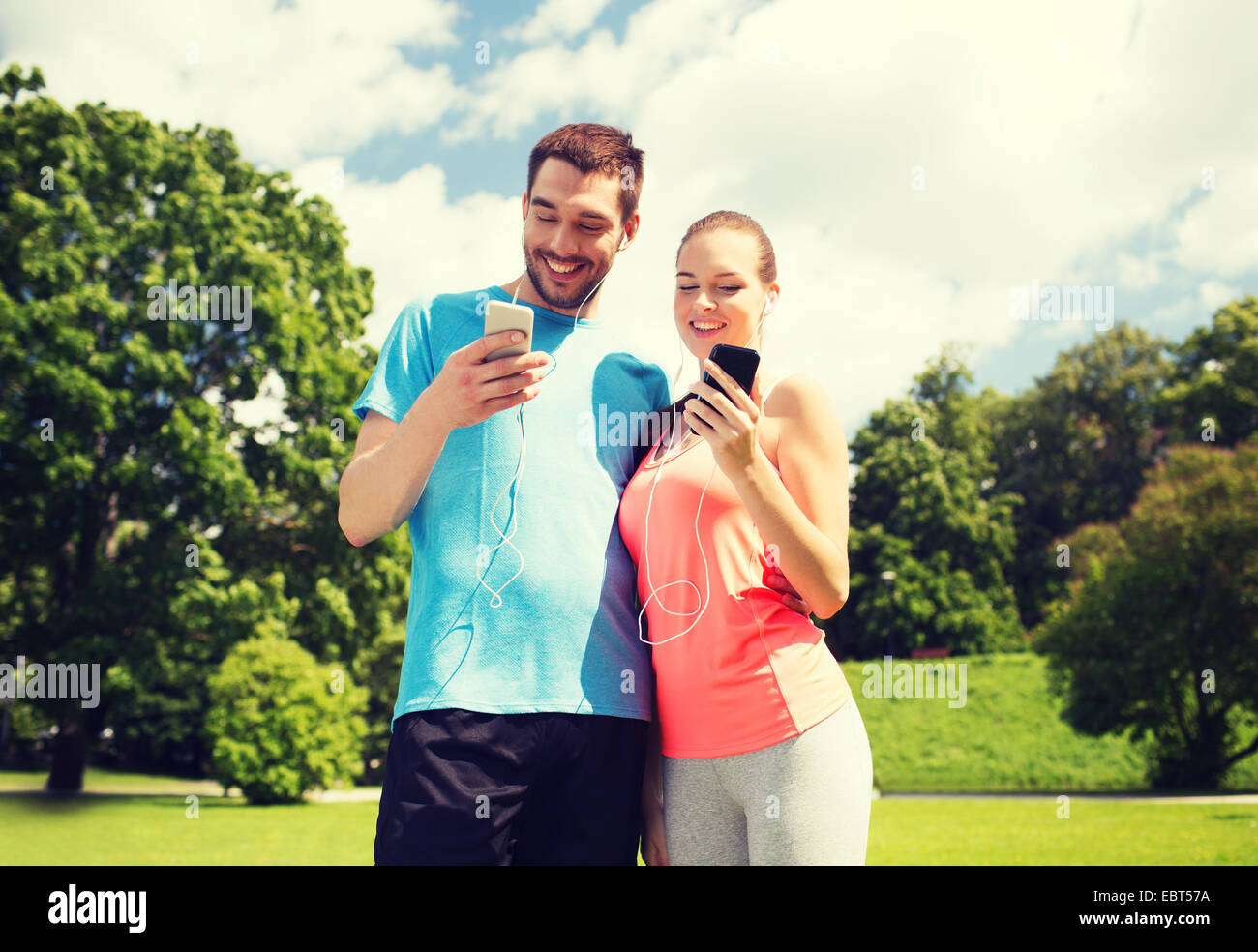 two smiling people with smartphones outdoors Stock Photo - Alamy