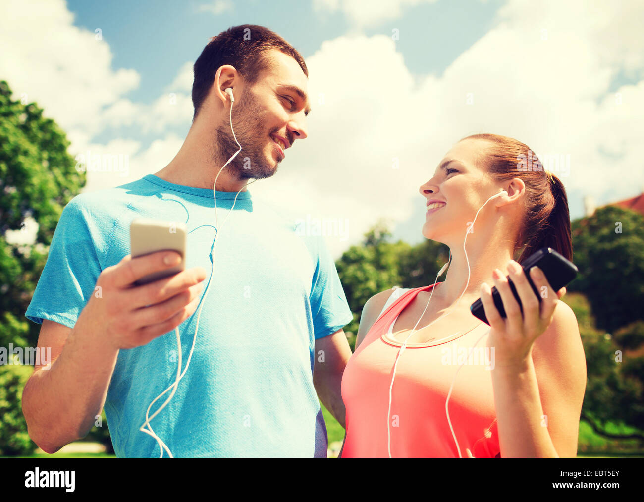 two smiling people with smartphones outdoors Stock Photo - Alamy