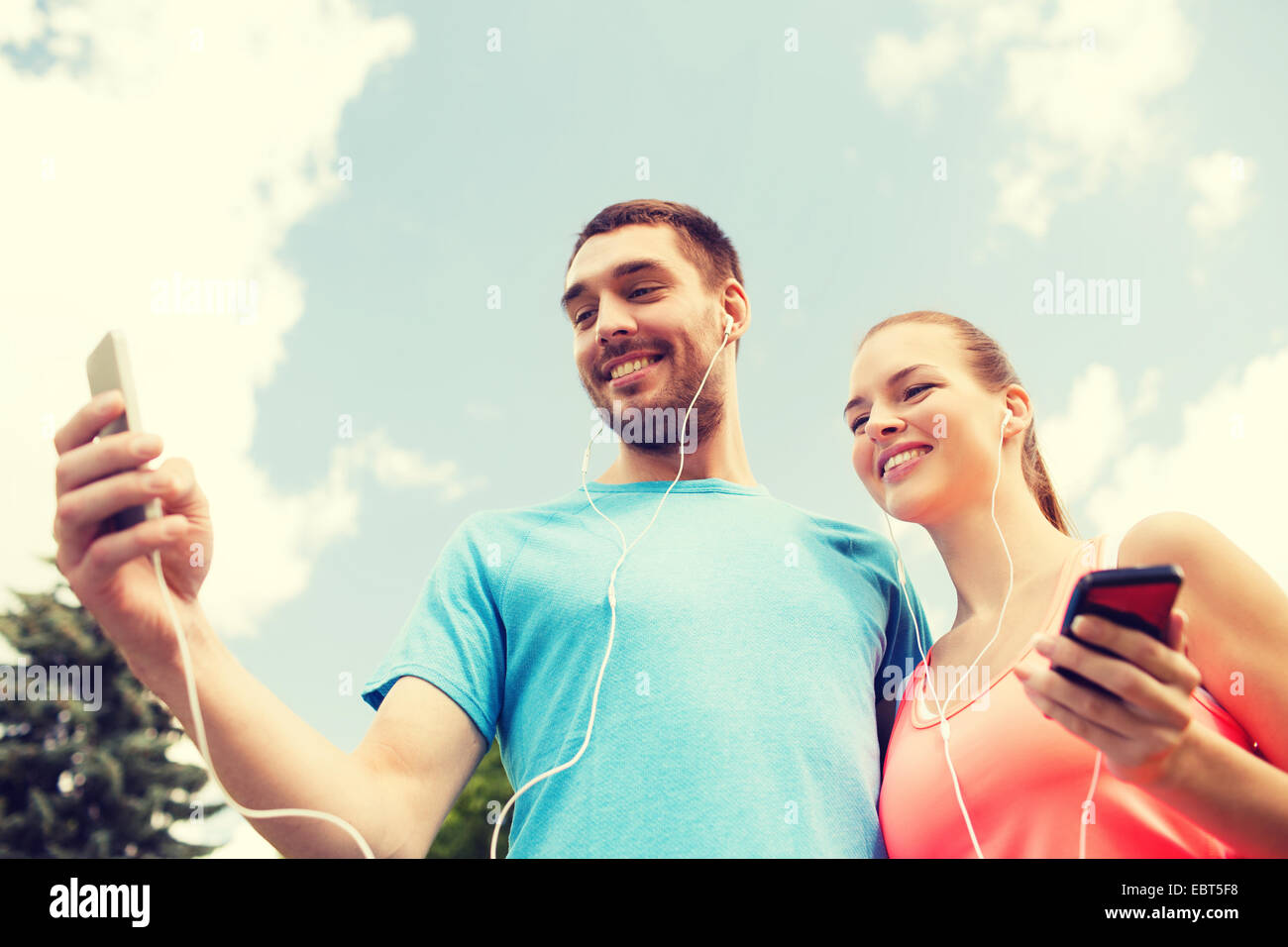 two smiling people with smartphones outdoors Stock Photo - Alamy