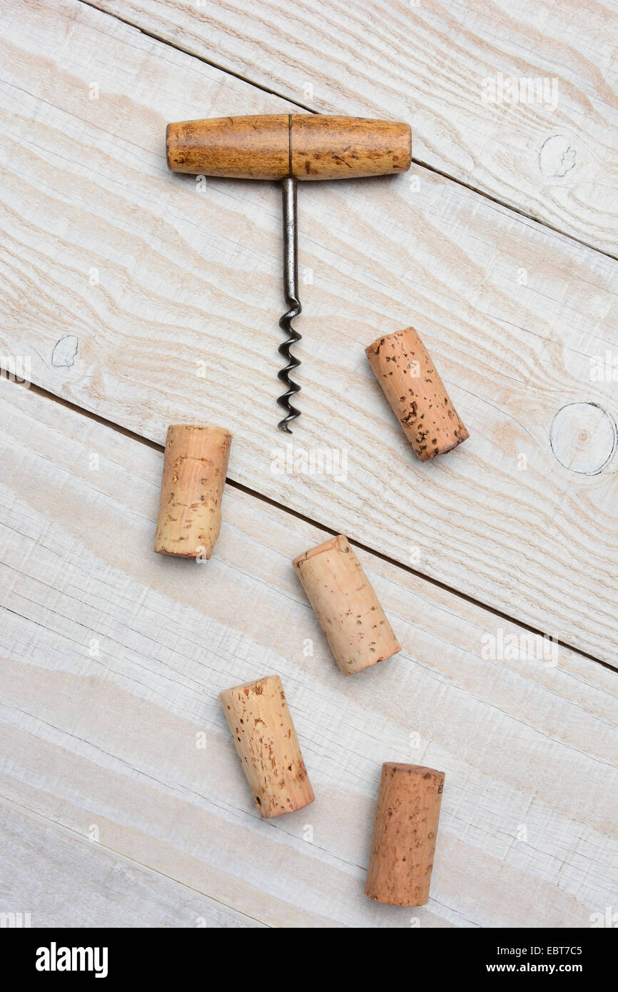 Closeup of an antique cork screw and five used corks on a rustic ...
