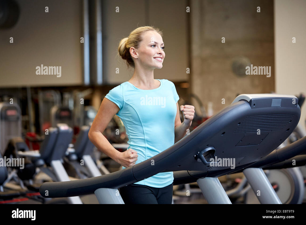 smiling woman exercising on treadmill in gym Stock Photo - Alamy