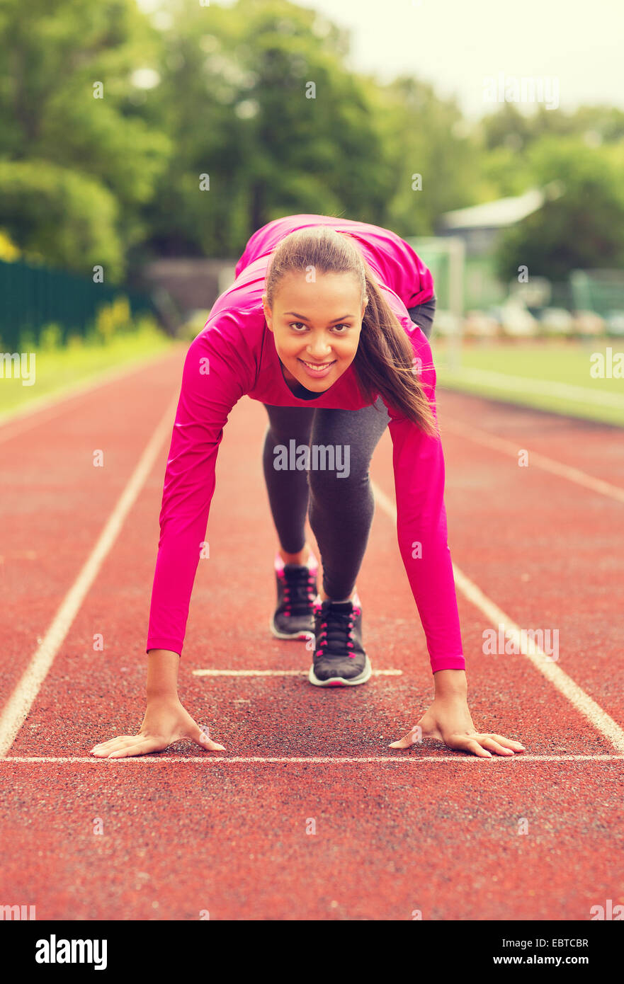 smiling young woman running on track outdoors Stock Photo - Alamy