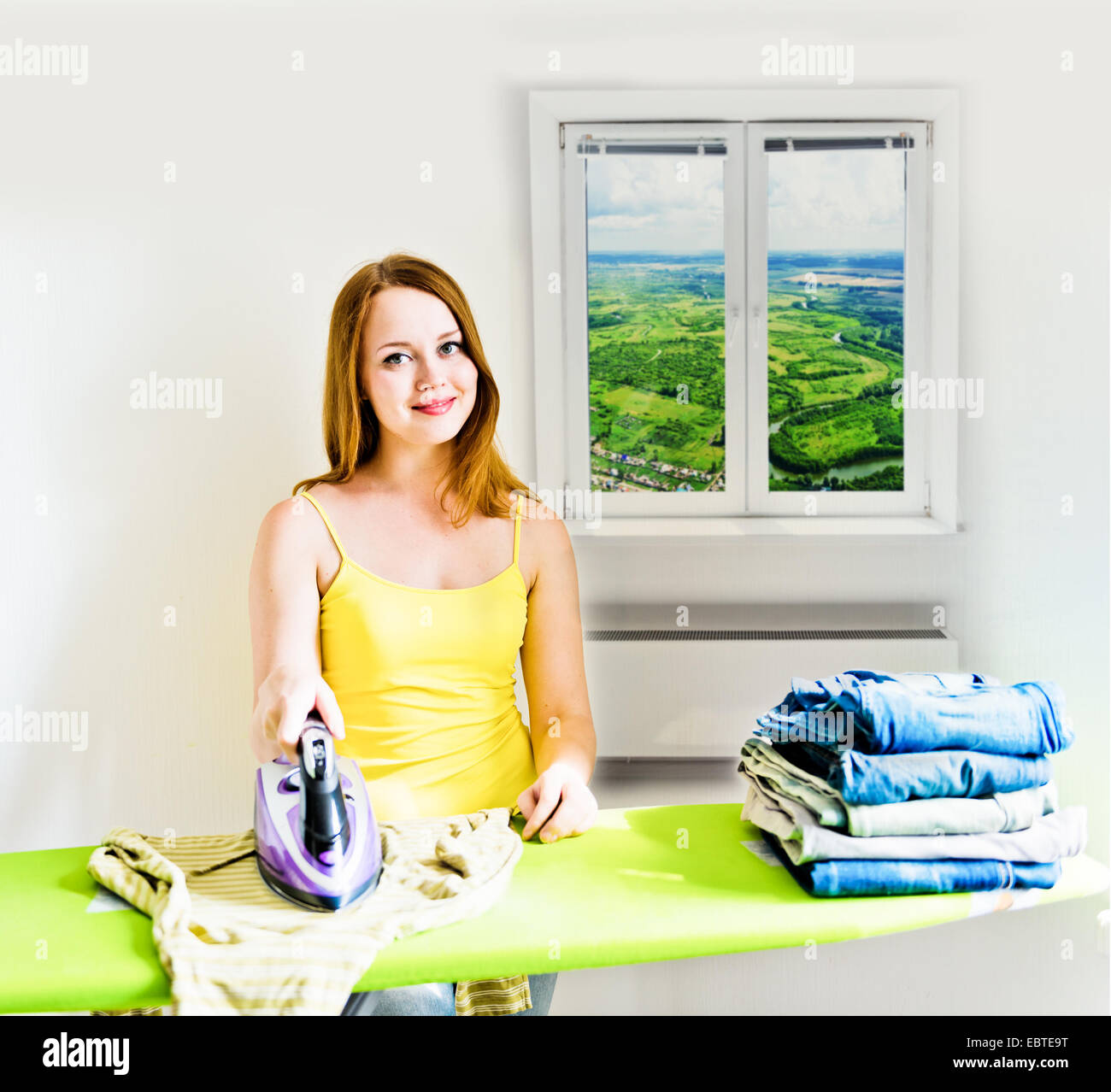 Happy young beautiful woman ironing clothes. Housework Stock Photo - Alamy