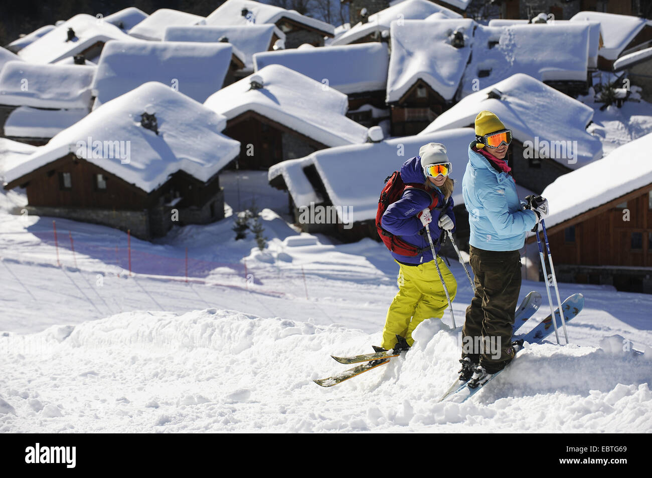 two skiers standing in front of snow covered mountain village, France ...