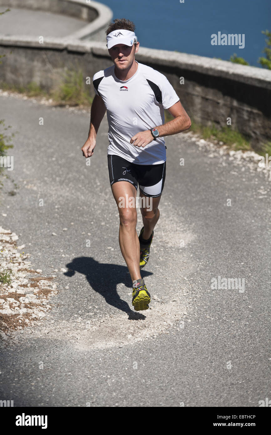man jogging up an asphalted path in the mountains high above Lake Garda ...
