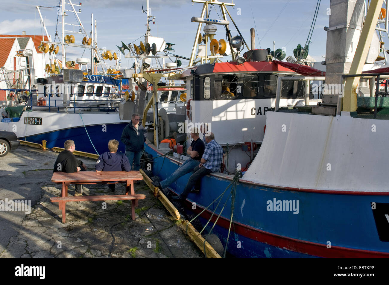 fishermen sitting by a trawler in harbour, Norway, Karmoy, Skudeneshavn ...