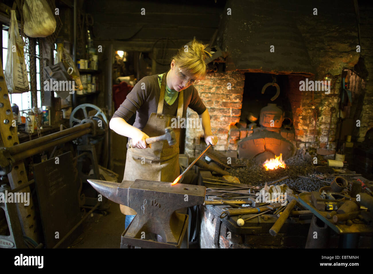 Woman blacksmith working in a forge, Much Hadham, Herfordshire, England ...