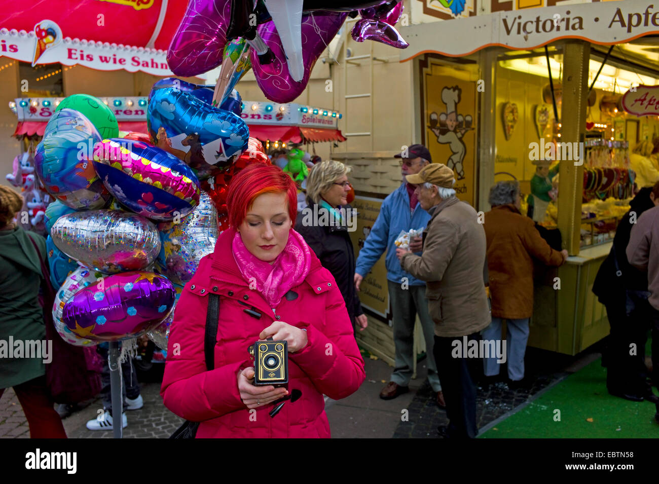 young red-haired woman talking pictures with an old camera at the ...