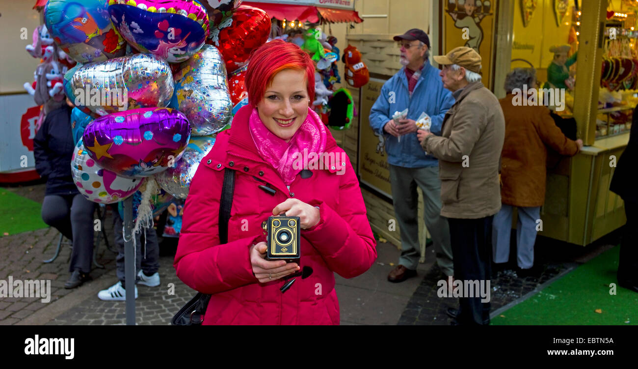 young red-haired woman talking pictures with an old camera at the ...
