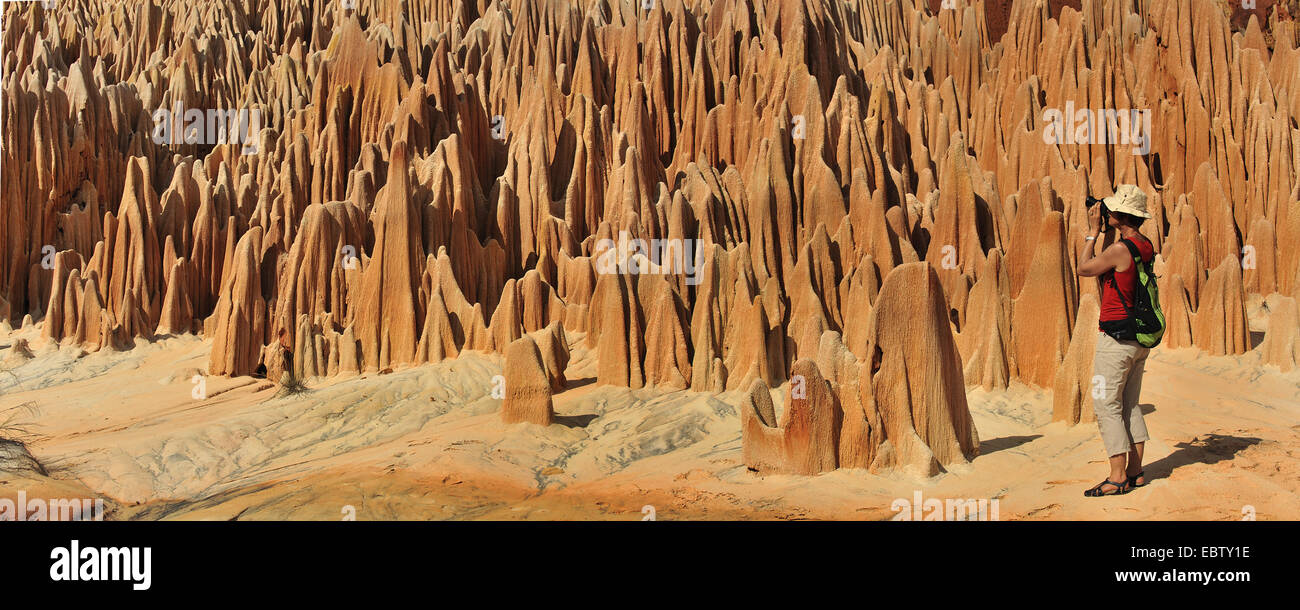 female tourist taking photos in red karst limestone formation ...